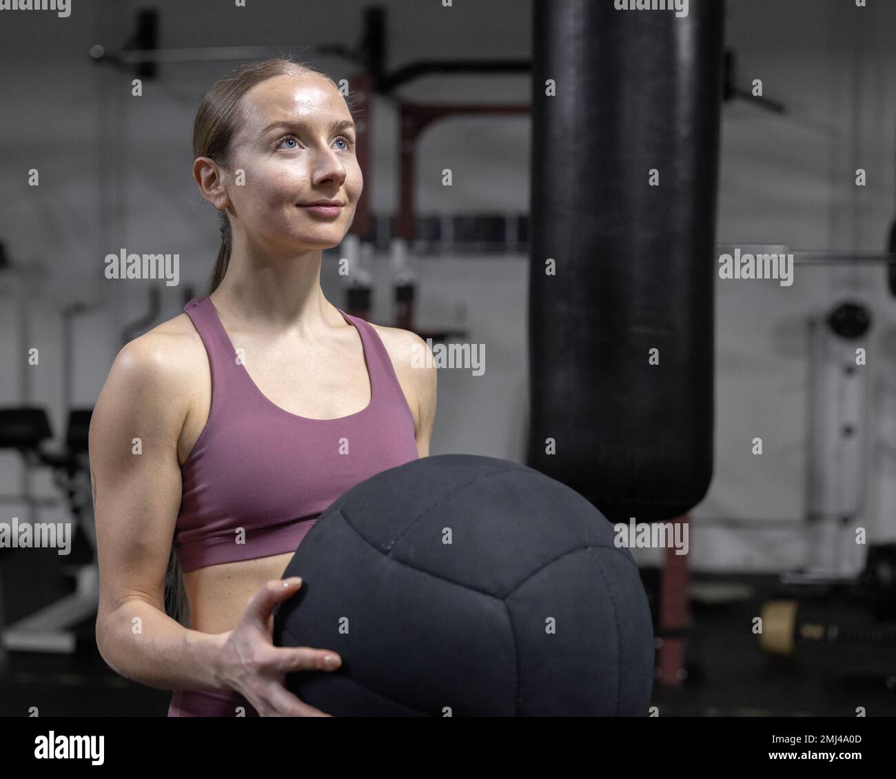 Long-haired, graceful boxer girl trains with a heavy ball in the gym ...