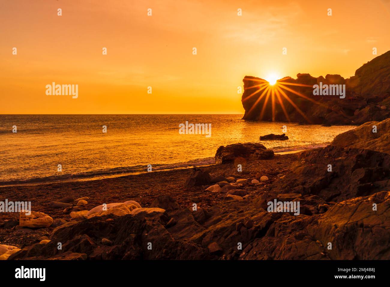 An epic sunset on the sea - the sun sets behind the mountain and ...
