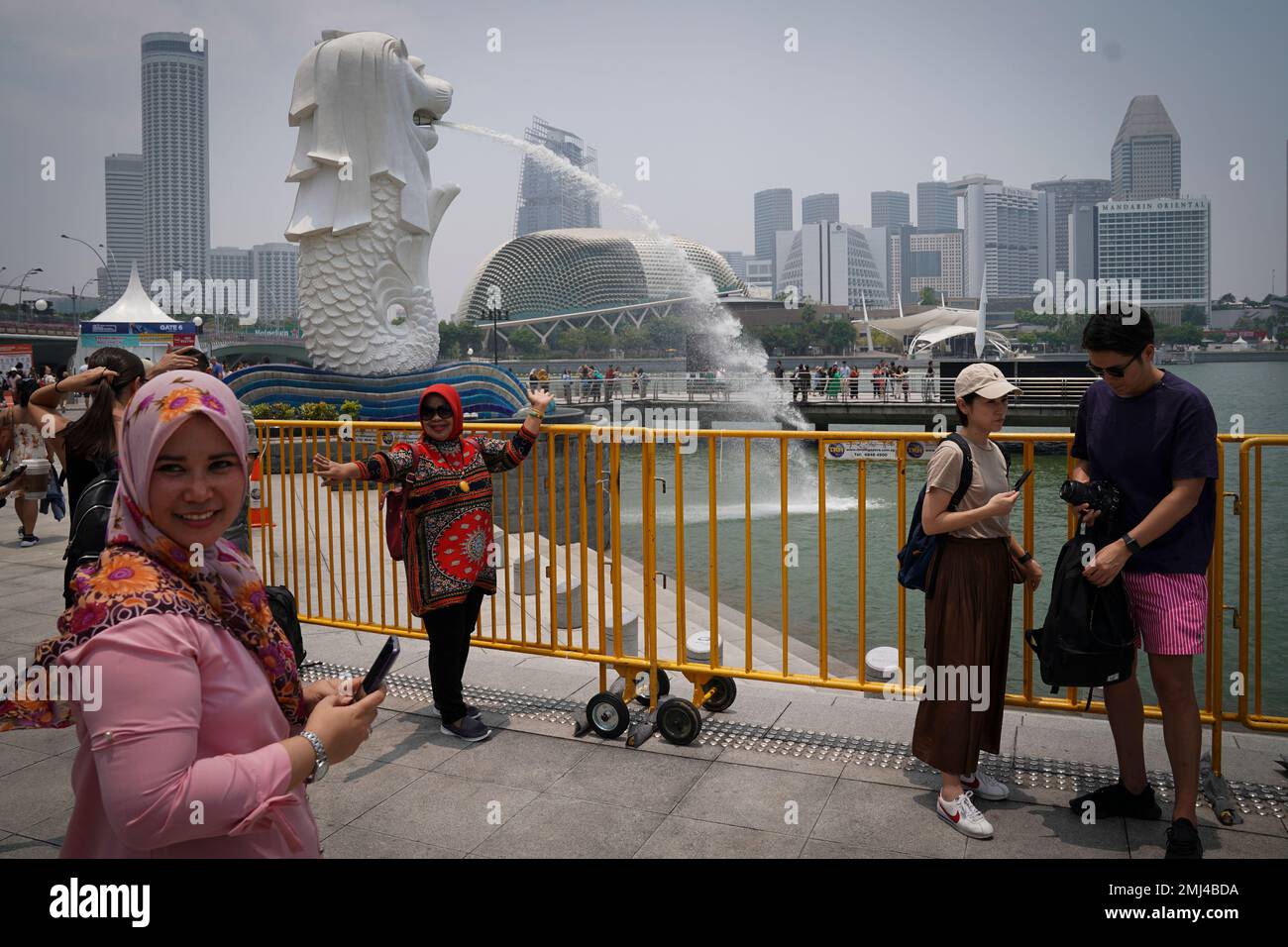 Tourists take photos in front of the iconic Merlion, mythical lion and ...