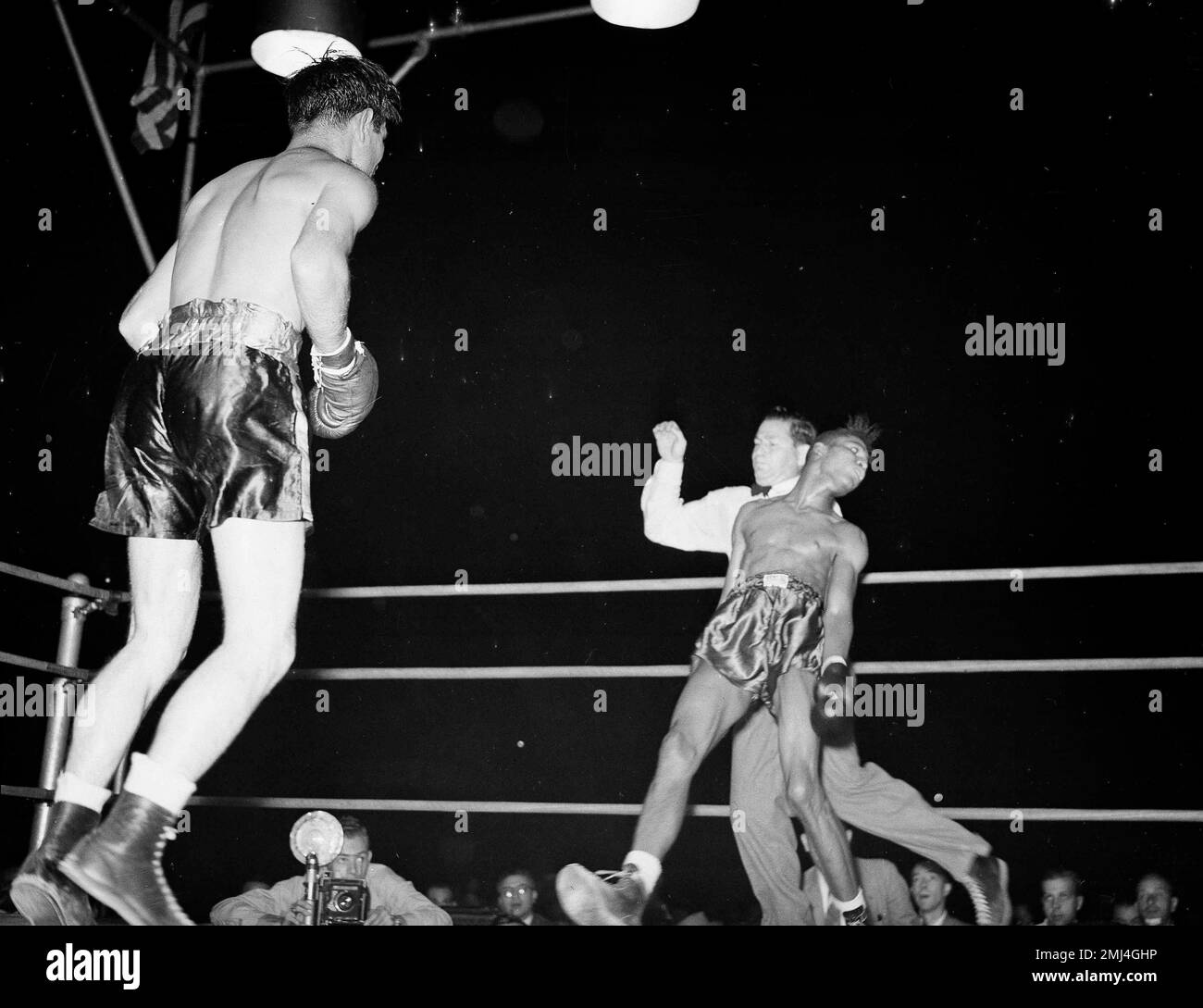 While the referee hustles out of the way, Sugar Ray Robinson reels ...