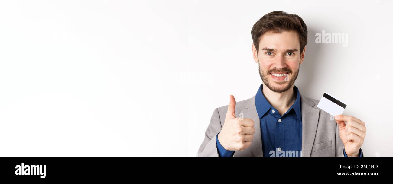 Shopping. Handsome satisfied client showing thumbs up and plastic ...