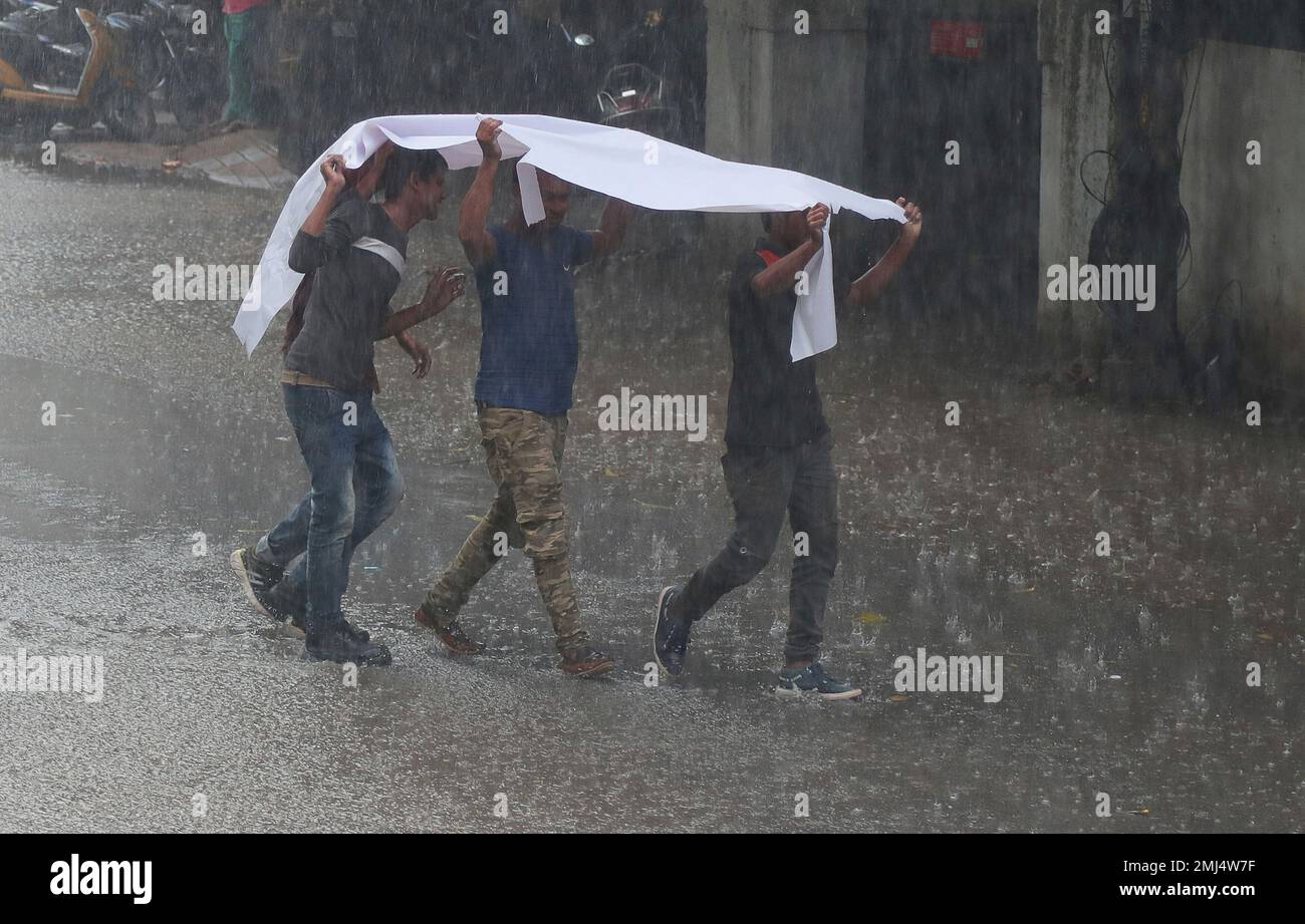 People use a plastic sheet to protect themselves from the rain in ...