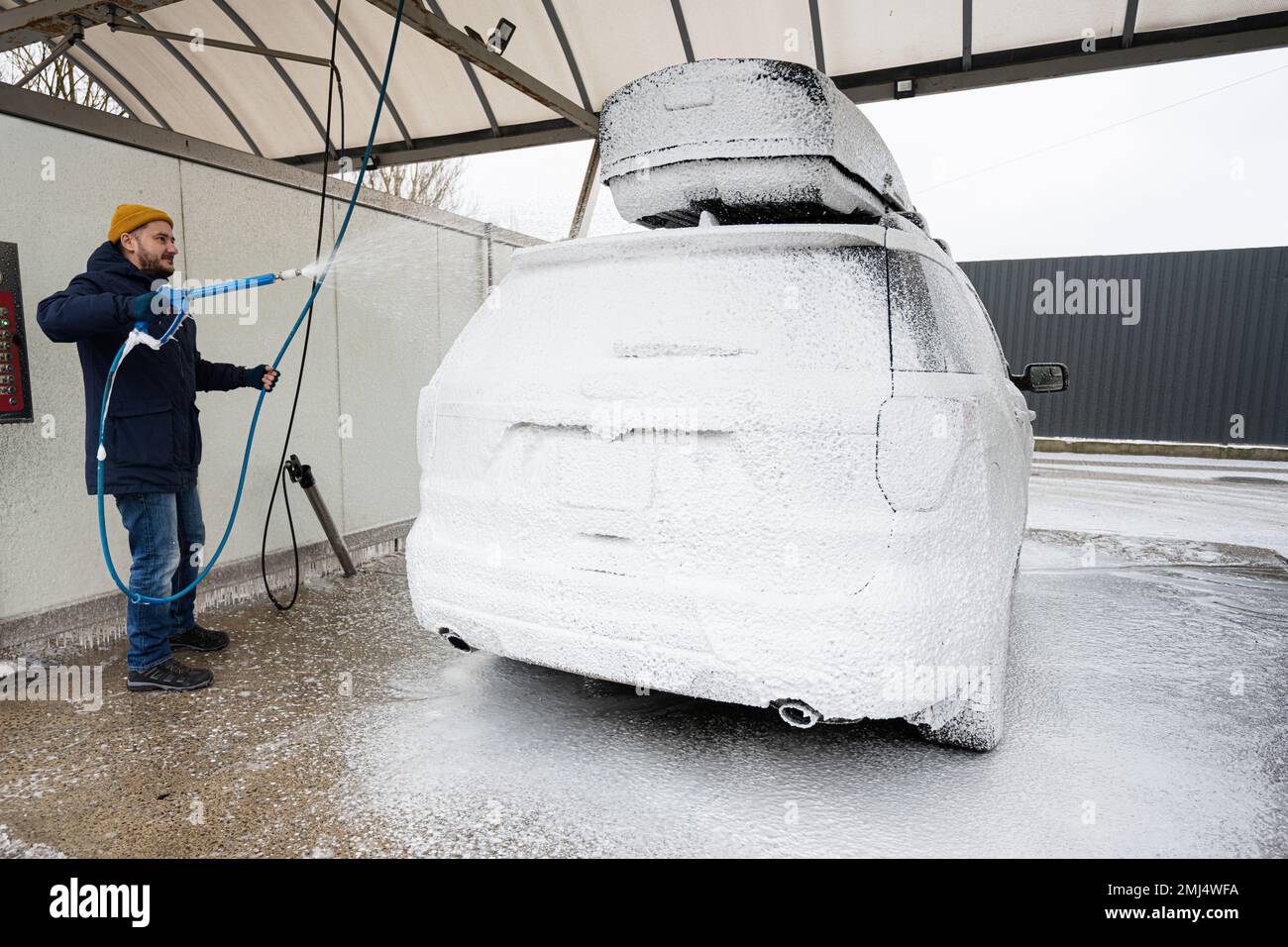 Man washing american SUV car with roof rack at a self service wash in ...
