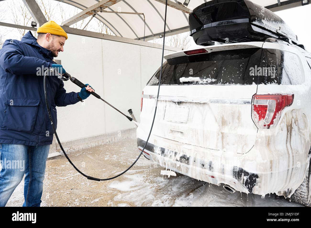 Man washing high pressure water american SUV car with roof rack at self ...