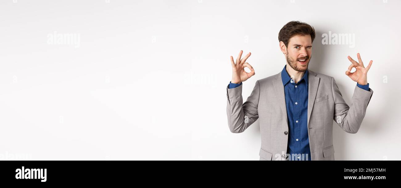 Cheeky handsome man in suit winking at you, showing okay signs, all ...