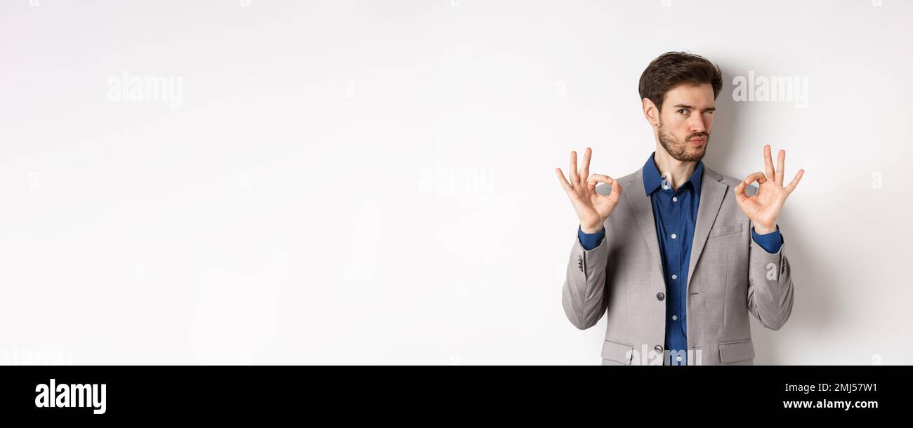 Very good. Handsome stylish guy in suit winking and showing okay sign ...