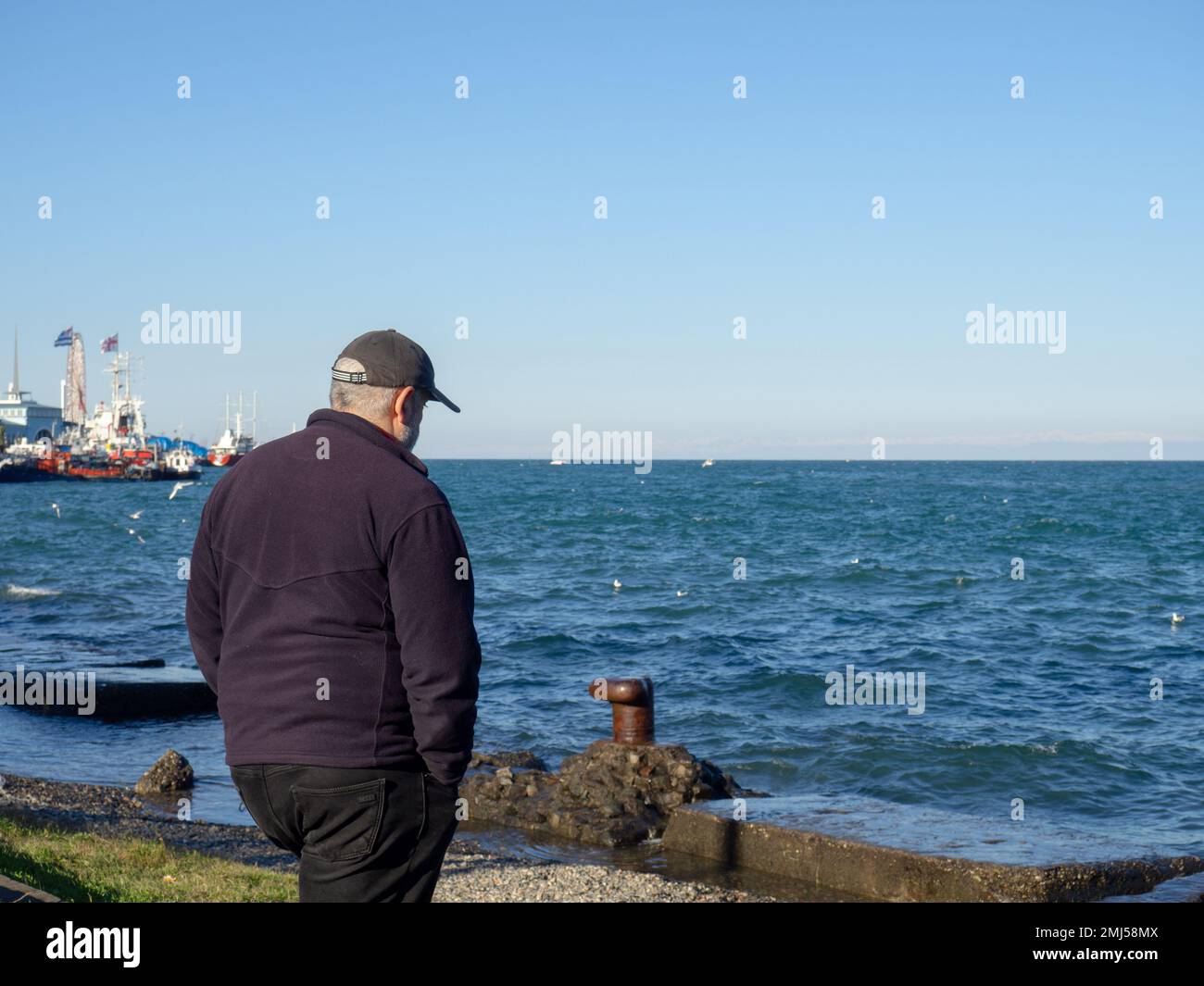 Lonely man on the pier. Photo from the back. The concept of thinking ...