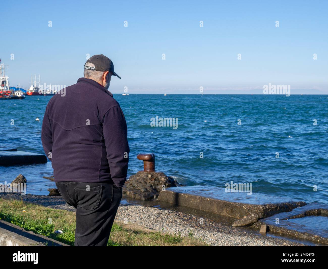 Lonely man on the pier. Photo from the back. The concept of thinking ...