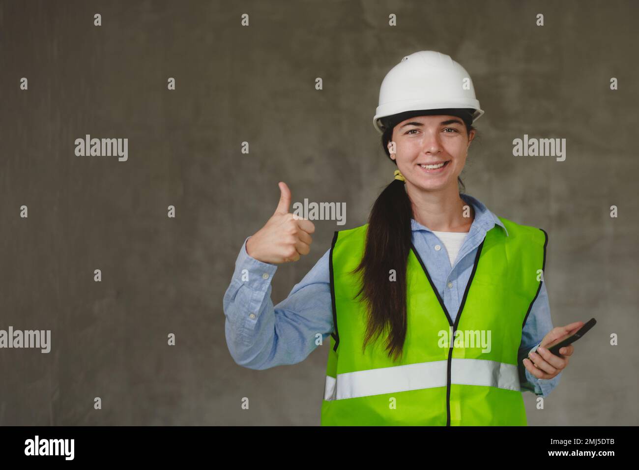 smiling foreman woman show thumbs up gesture on concrete wall ...