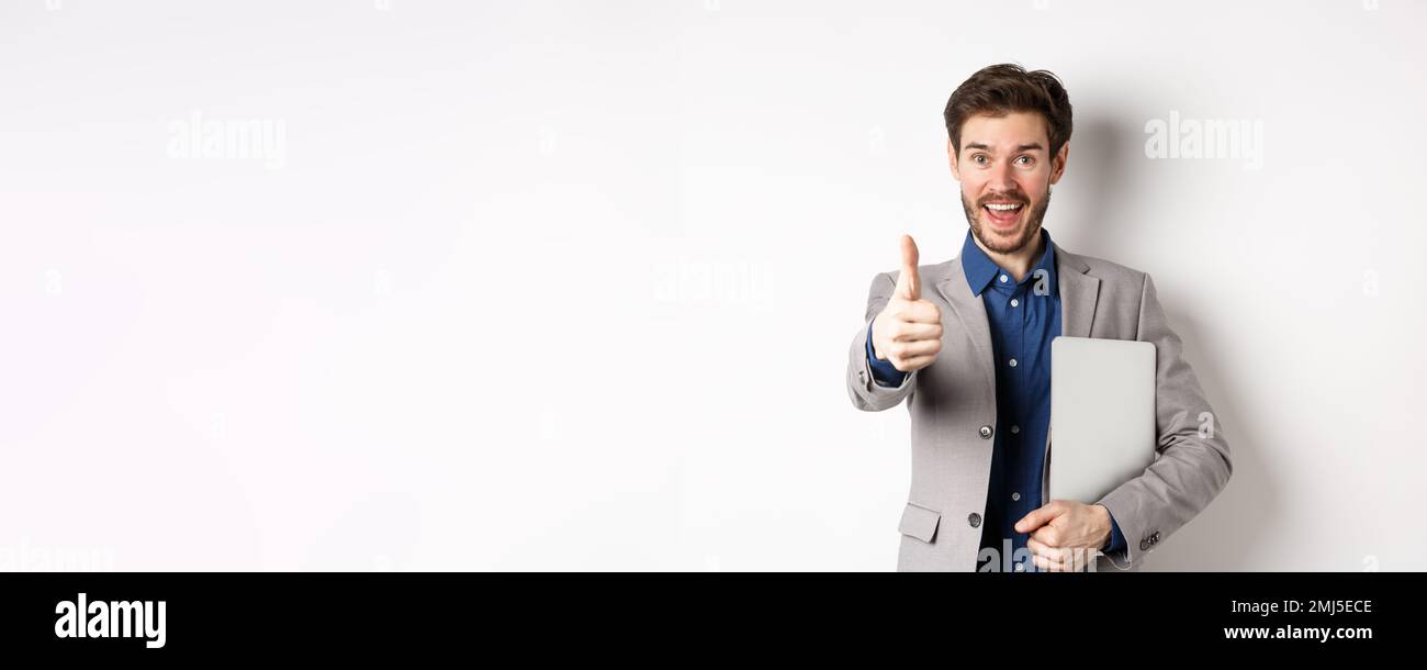 Good job. Happy smiling business man in suit holding laptop, showing ...
