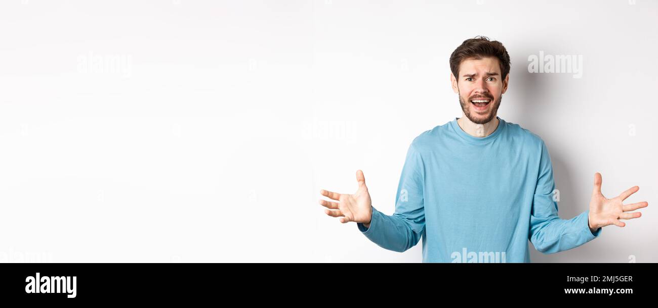 Image of frustrated and worried young man shaking hands, trying to ...