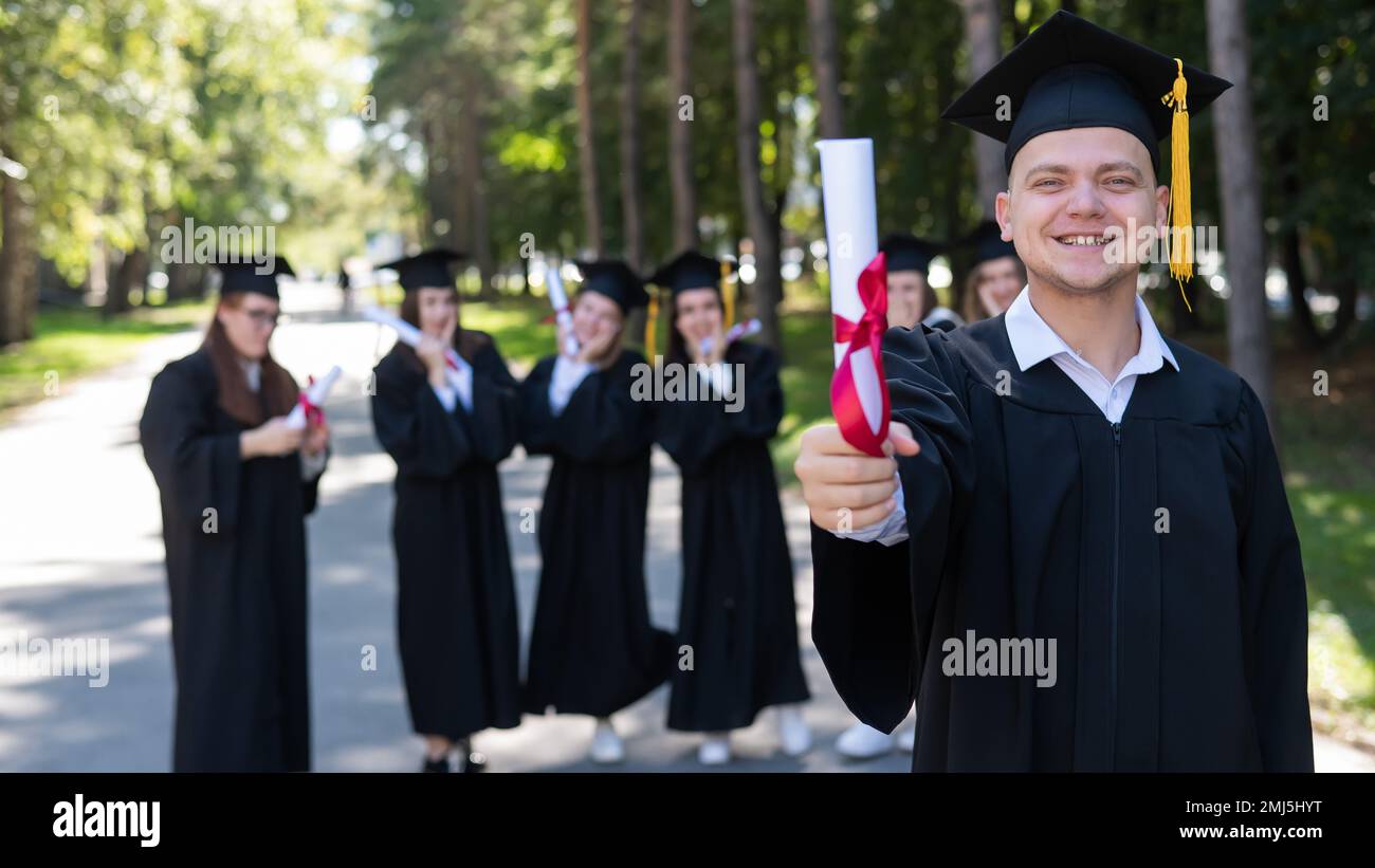 Happy young caucasian man celebrating graduation. Crowd of students ...