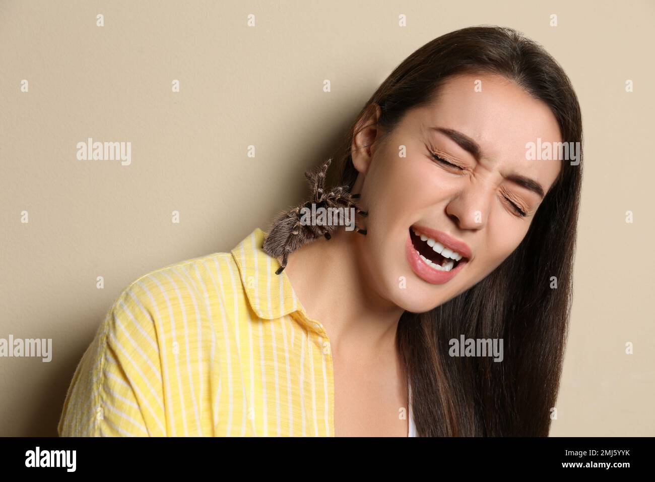 Scared young woman with tarantula on beige background. Arachnophobia ...
