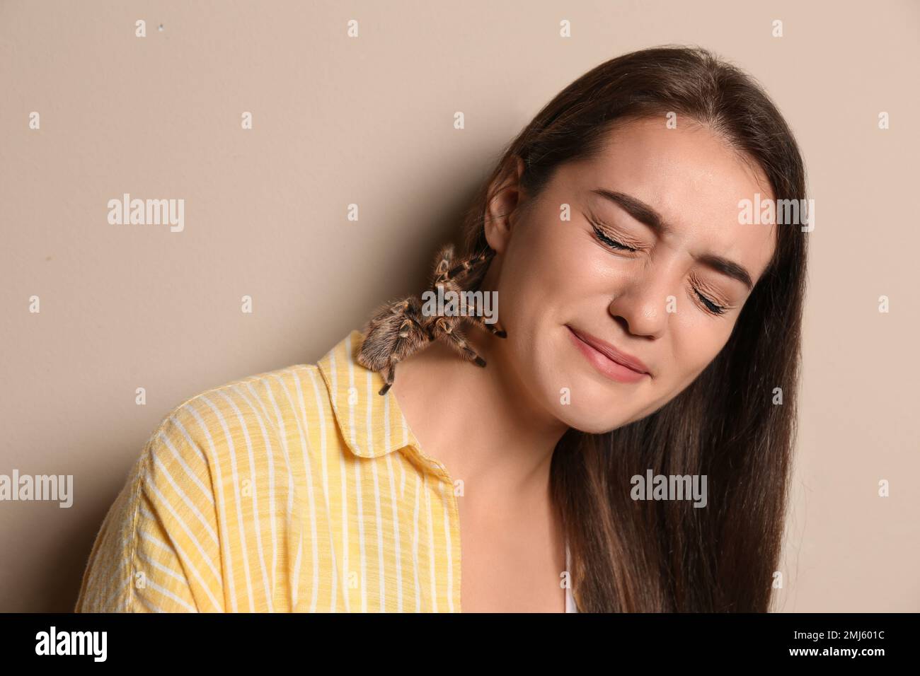 Scared young woman with tarantula on beige background. Arachnophobia ...