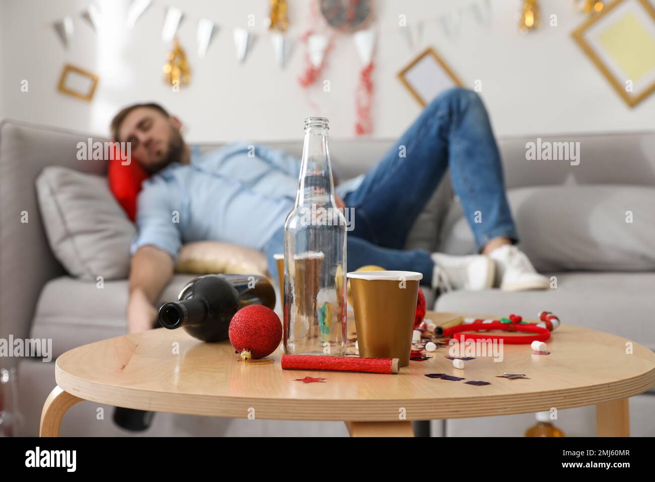 Drunk man sleeping in room after New Year party, focus on messy table ...