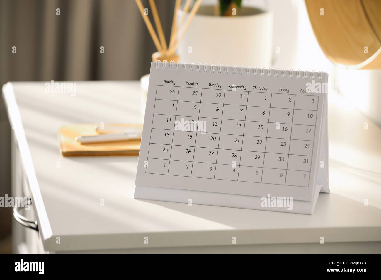 Paper calendar on white chest of drawers indoors Stock Photo - Alamy