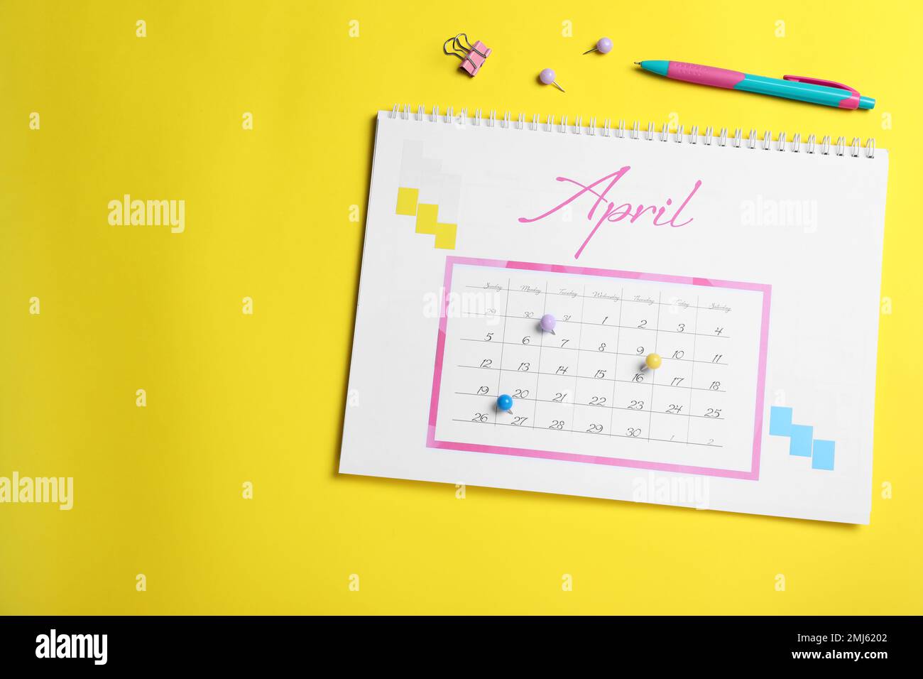 Calendar page marked with drawing pins on yellow background, flat lay ...