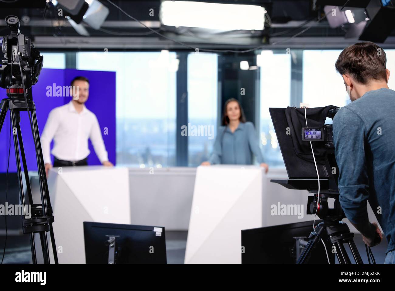 Presenters and video camera operator working in studio. News ...