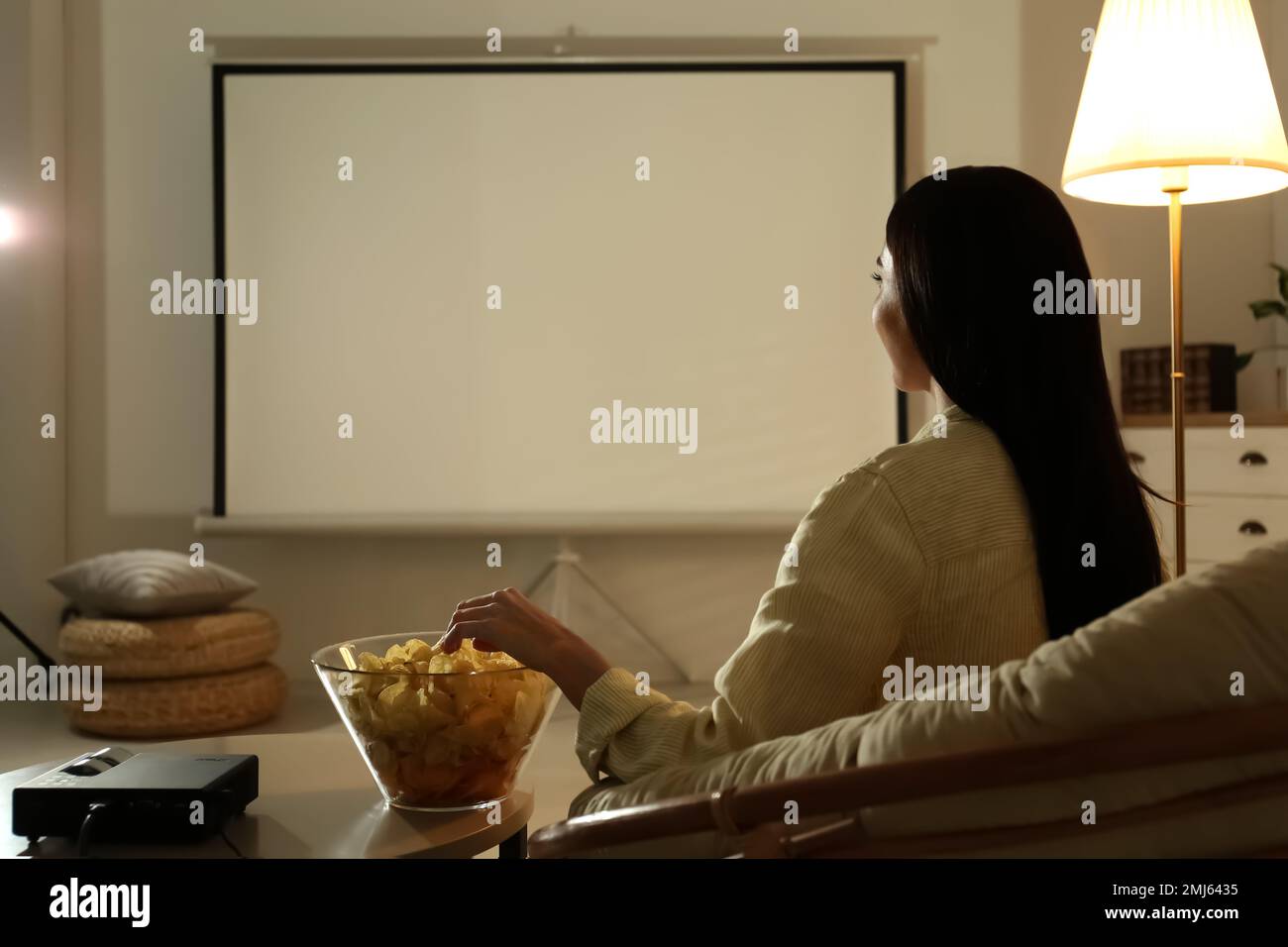 Young woman watching movie using video projector at home Stock Photo ...