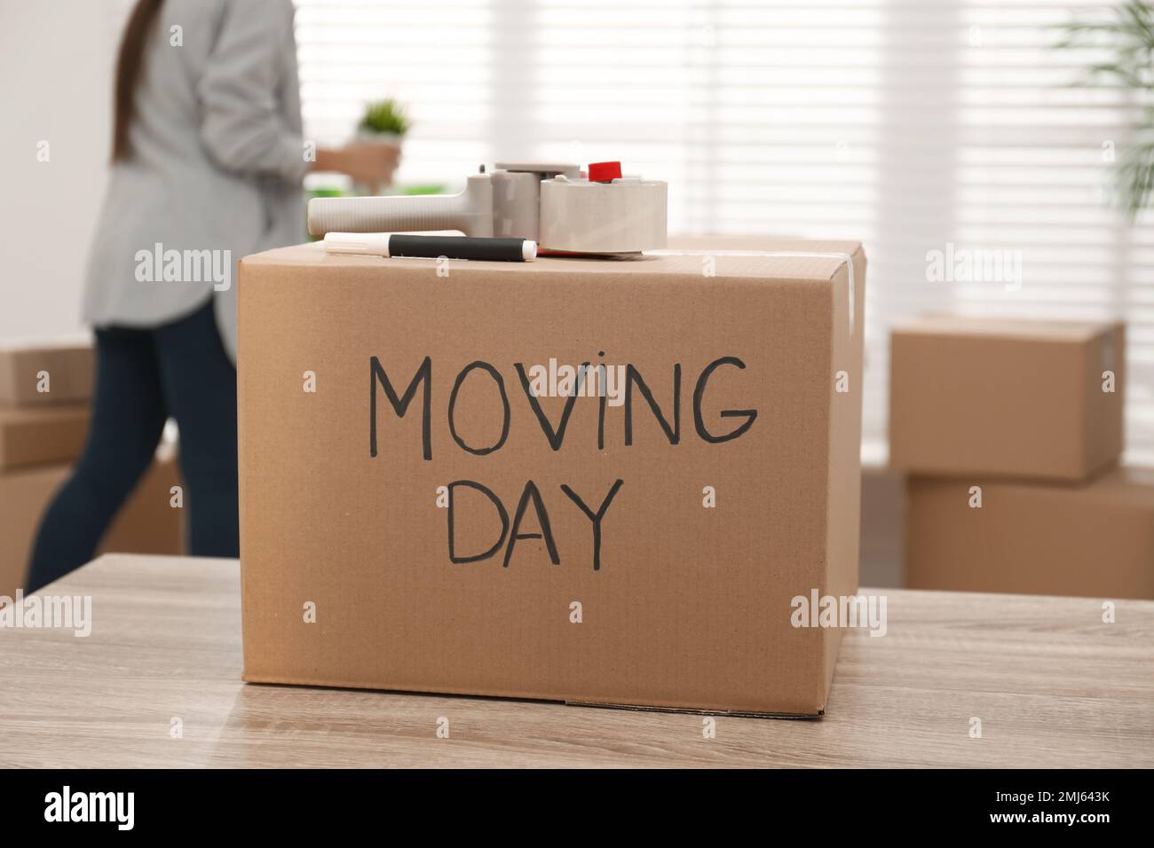 Cardboard box with words MOVING DAY and packaging items on wooden table ...