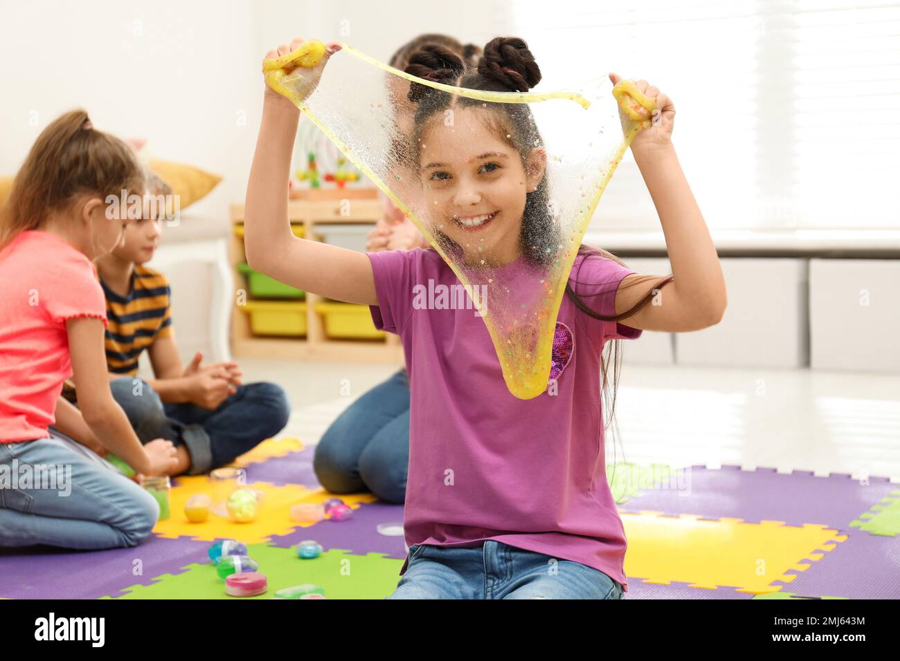 Happy little girl playing with slime in room Stock Photo - Alamy