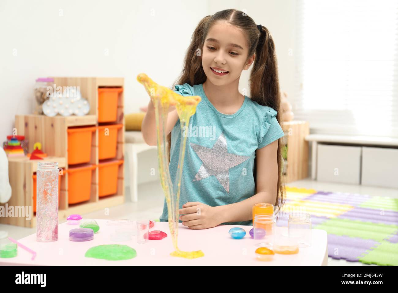 Preteen girl playing with slime at table indoors Stock Photo - Alamy