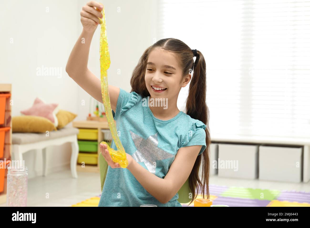 Preteen girl playing with slime in room Stock Photo - Alamy