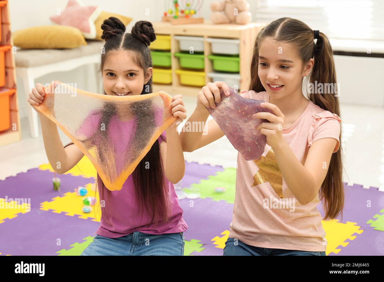 Happy girls playing with slime in room Stock Photo - Alamy