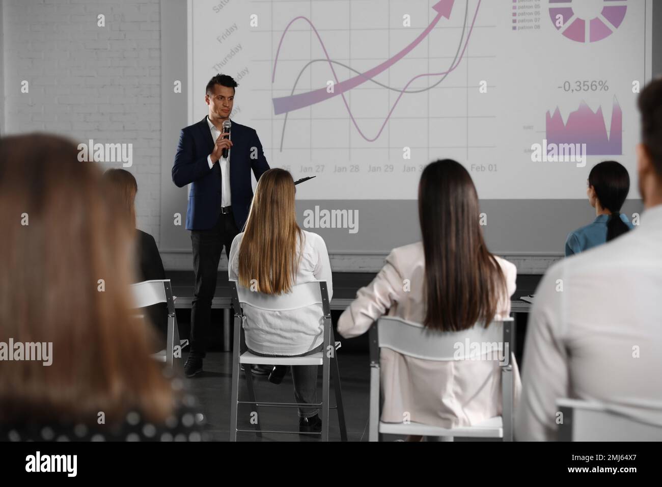 Male business trainer giving lecture in conference room with projection ...