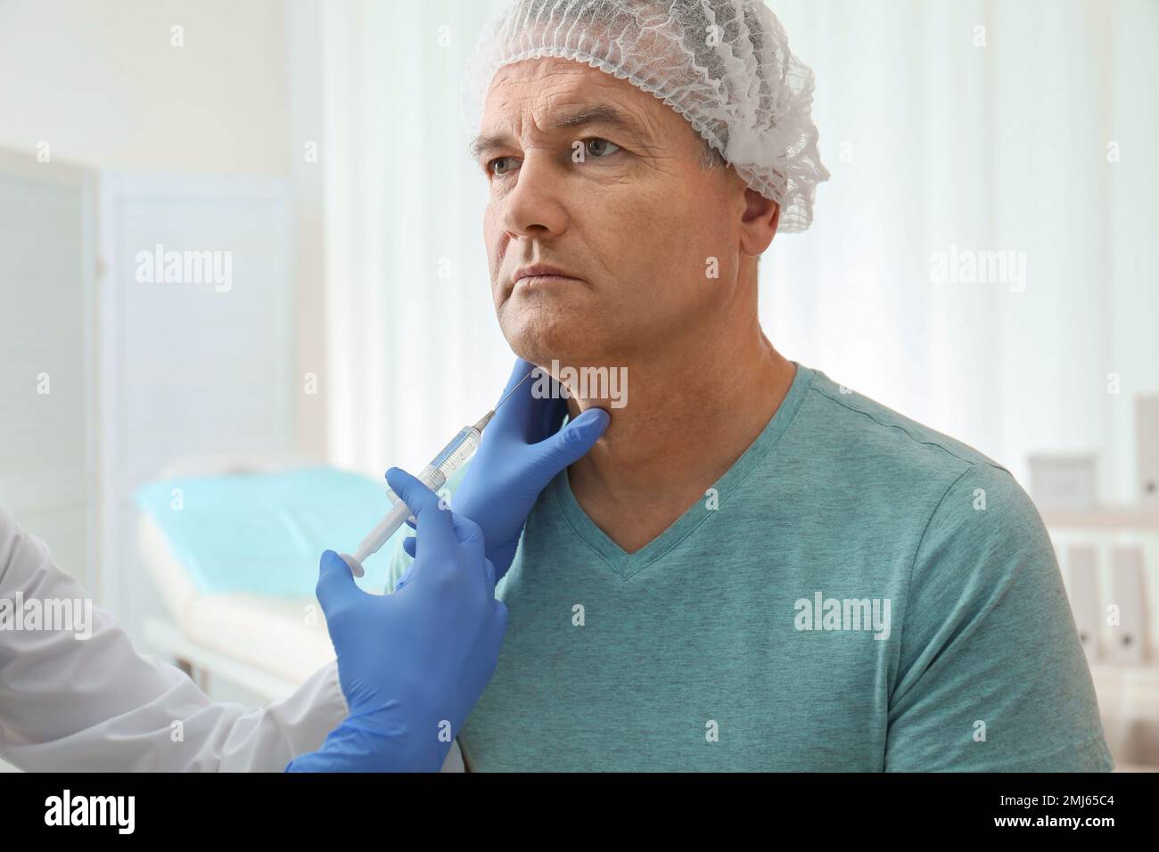 Mature man with double chin receiving injection in clinic Stock Photo ...