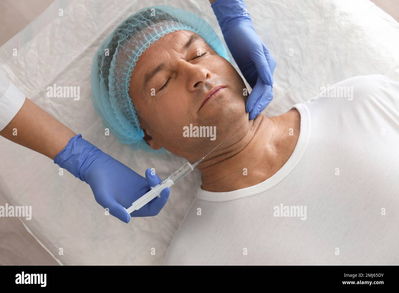 Mature man with double chin receiving injection in clinic, above view ...