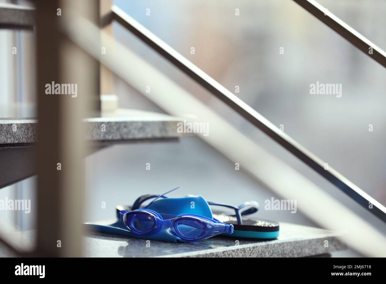 Swimming cap, goggles and flip flops on stairs indoors Stock Photo - Alamy