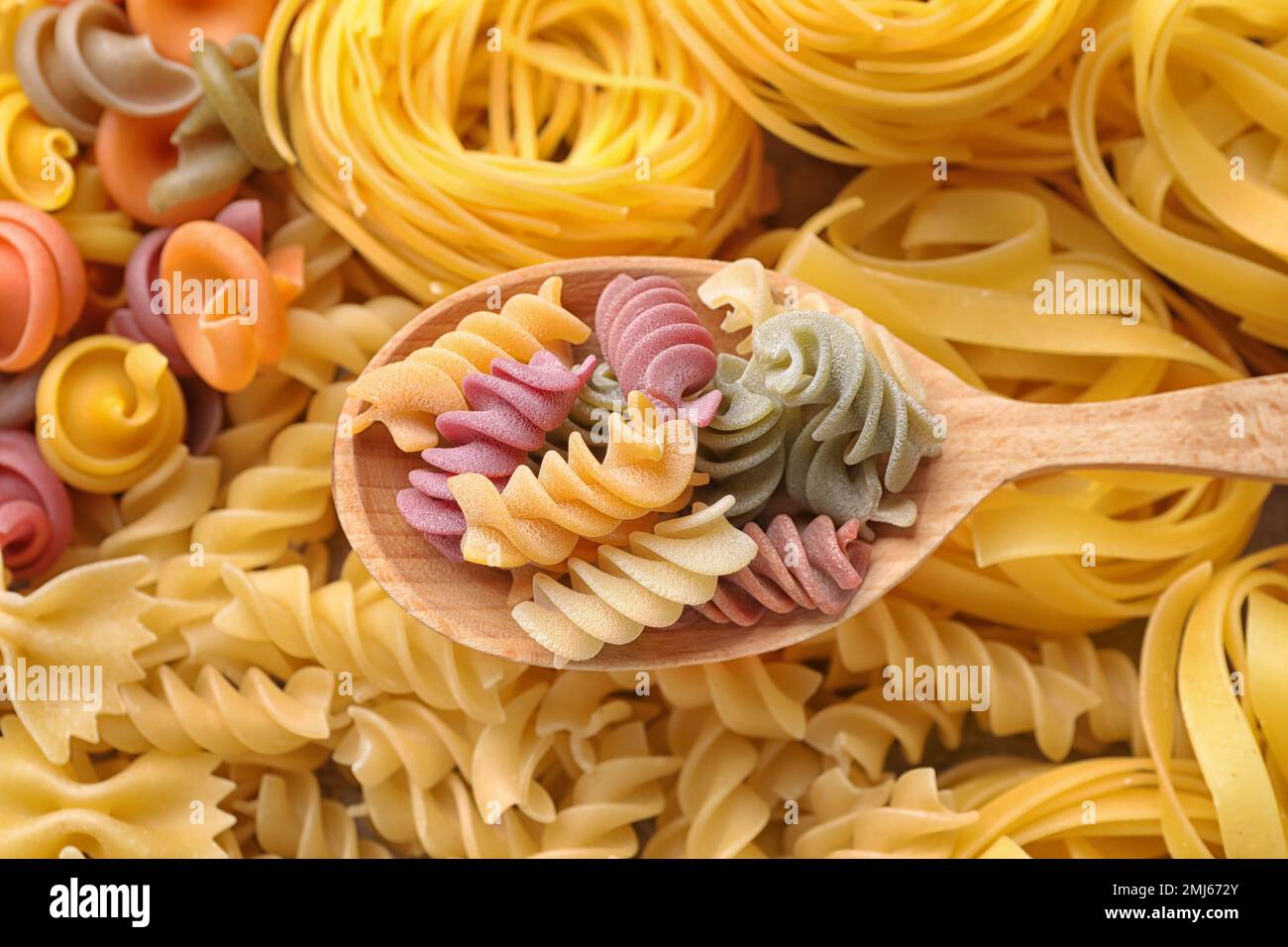 Wooden spoon and different types of pasta as background, top view Stock ...