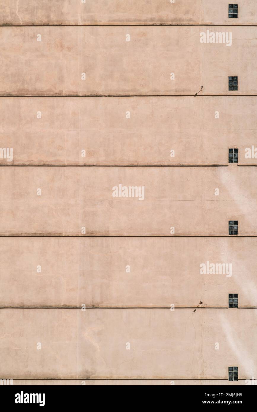 A vertical shot of a residential building wall with a sequence of small ...