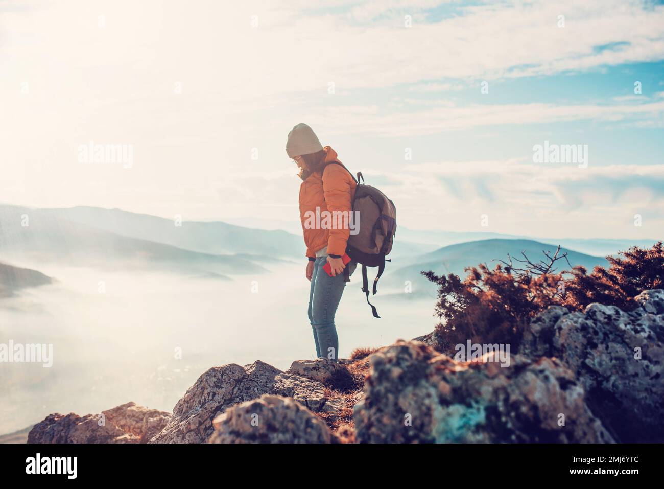 Cheering woman backpacker enjoy the view on sunrise mountain top cliff ...
