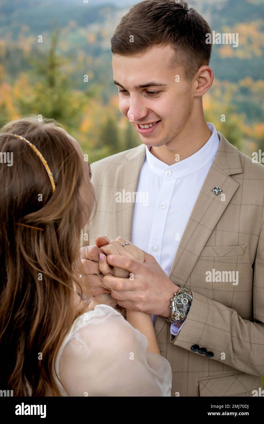 The bride looks at the groom with loving eyes. Smiling newlyweds look ...