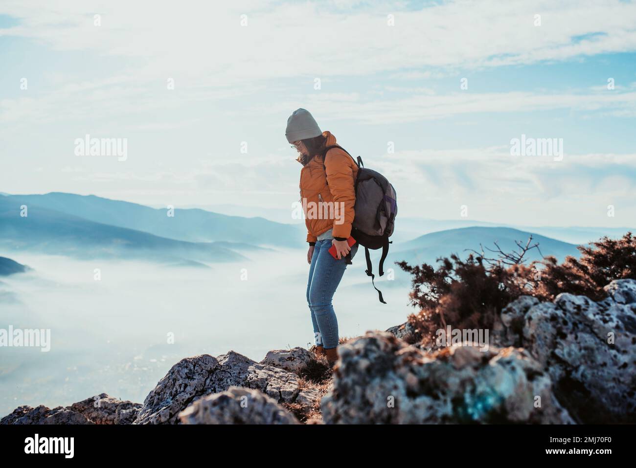 a hiking girl with a backpack on her back watches the morning from the ...