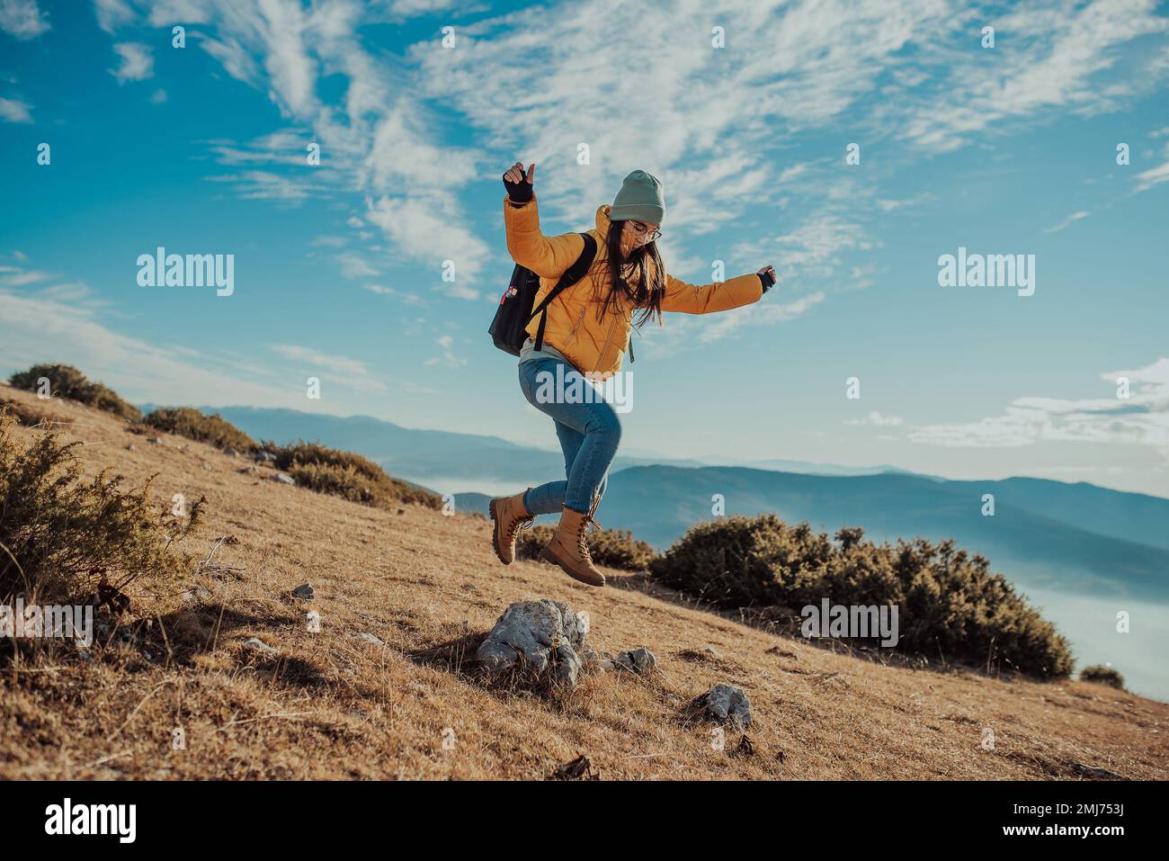 Cheering woman backpacker enjoy the view on sunrise mountain top cliff ...