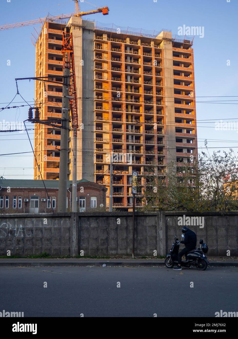 A man on a moped parked on the side of the road. at the building under ...
