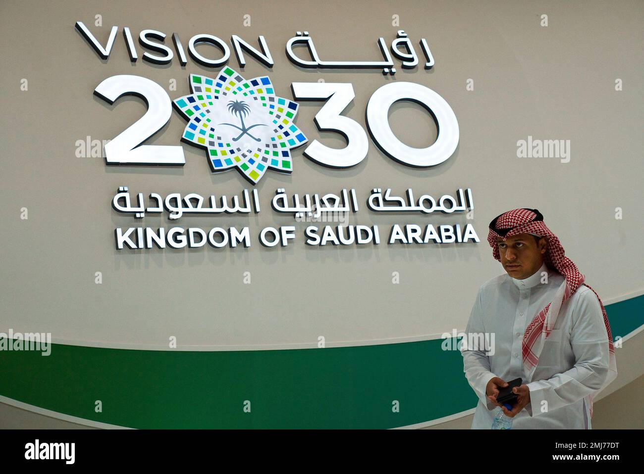 A Saudi man walks past a "Vision 2030" display at a stand about Saudi ...