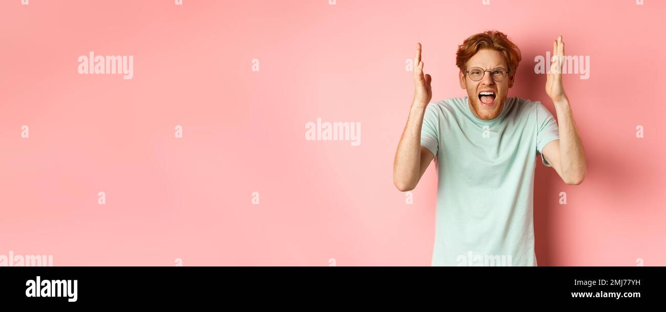 Angry redhead guy in glasses shouting, frowning and shaking hands with ...