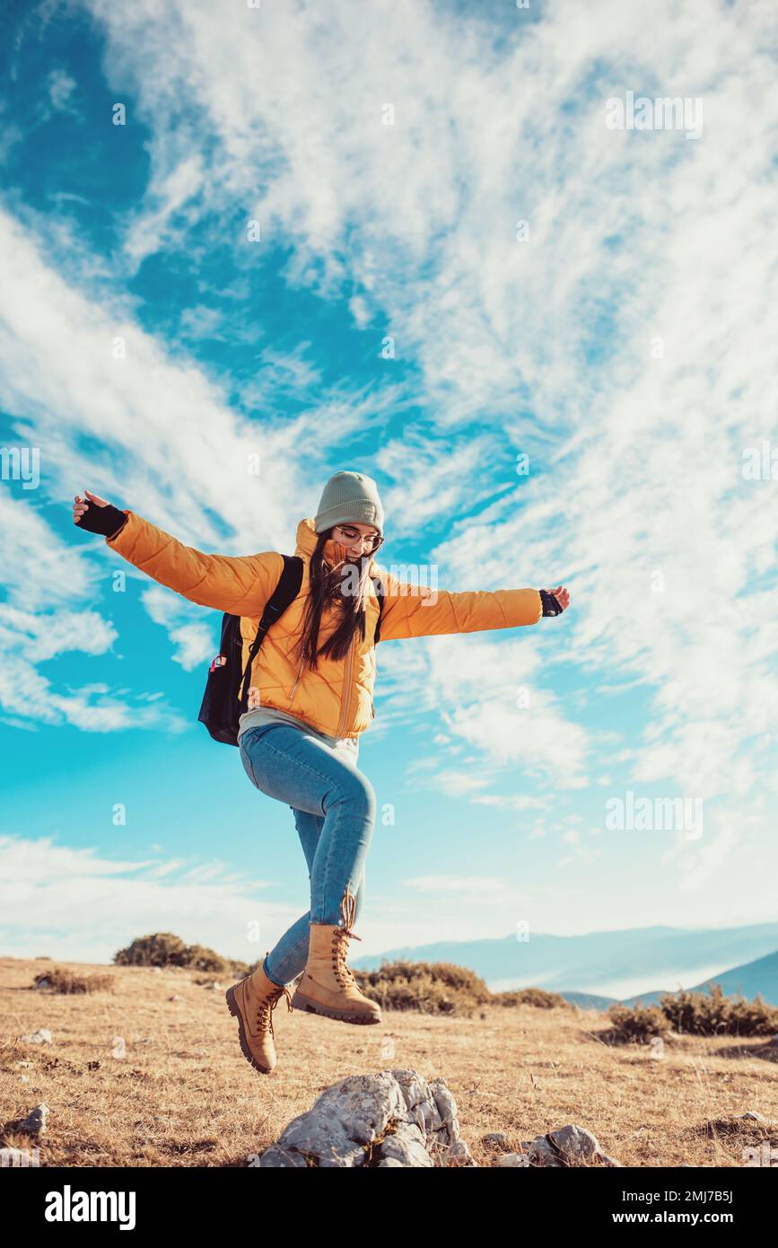 Cheering woman backpacker enjoy the view on sunrise mountain top cliff ...