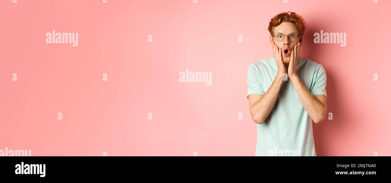 Shocked redhead man gossiping, staring impressed at camera and touching ...