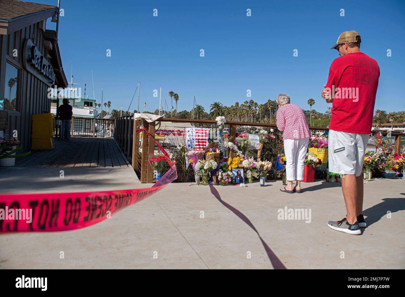 People gather around a memorial for the victims of the Conception dive ...