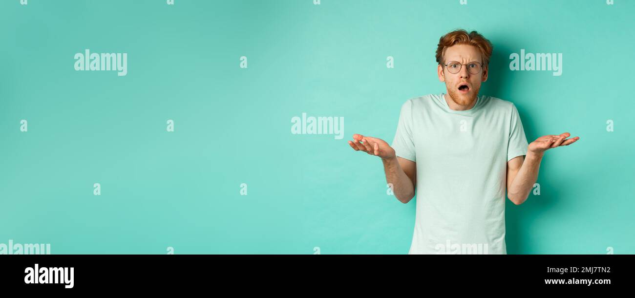 Confused and shocked guy with red messy hair and glasses, shrugging and ...