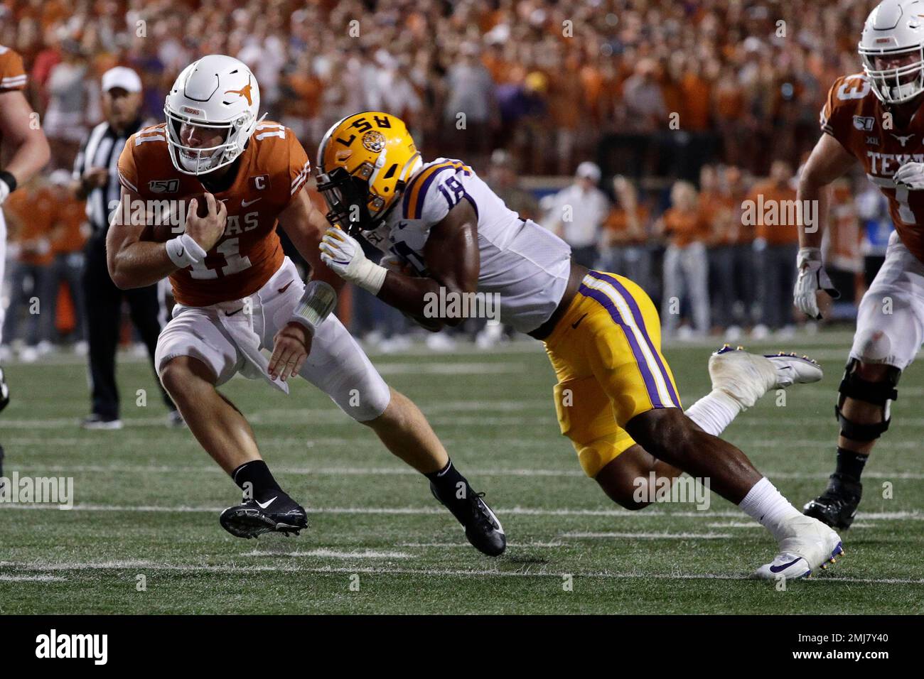 Texas quarterback Sam Ehlinger tries to break a tackle by LSU ...