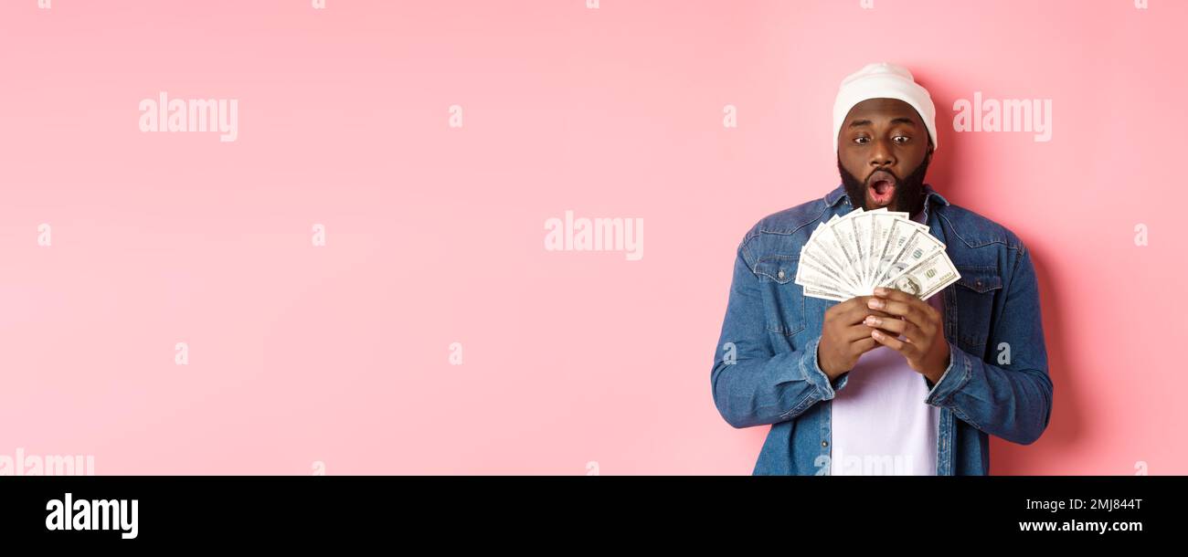 Amazed african-american man receive cash prize, showing money and ...