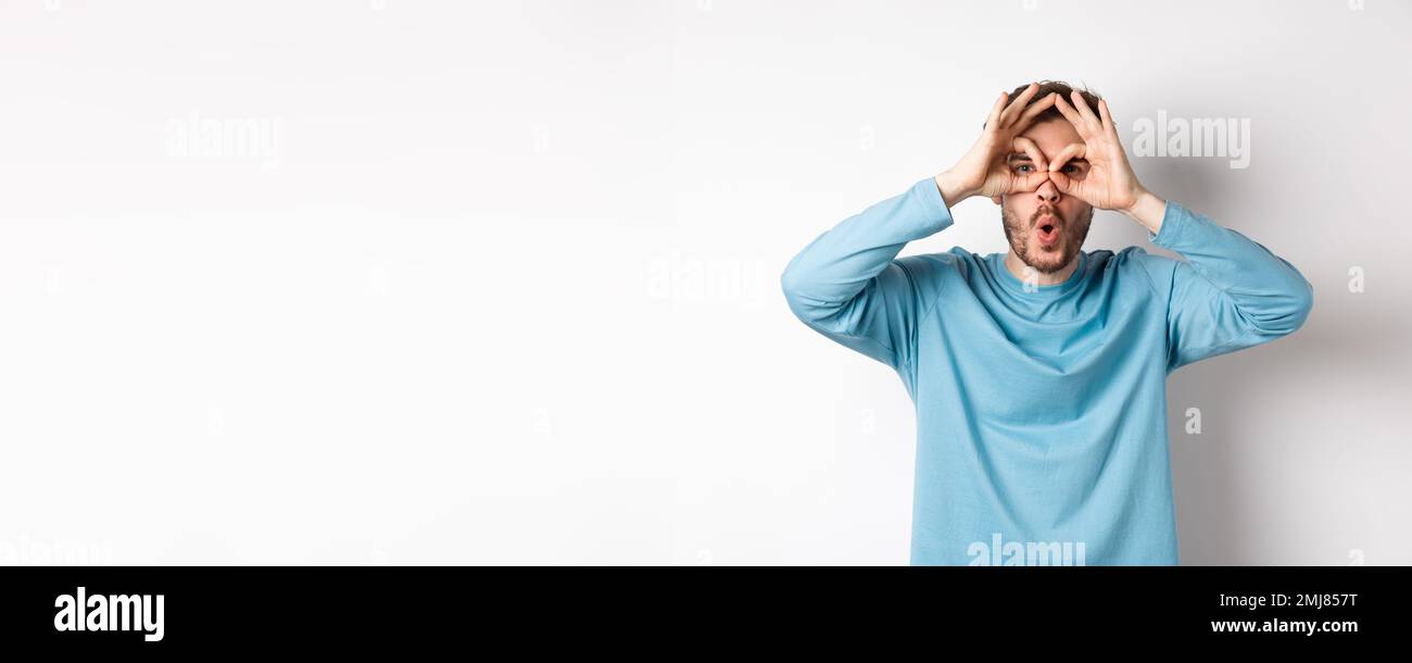 Check it out. Impressed young man seeing awesome promo, looking through ...