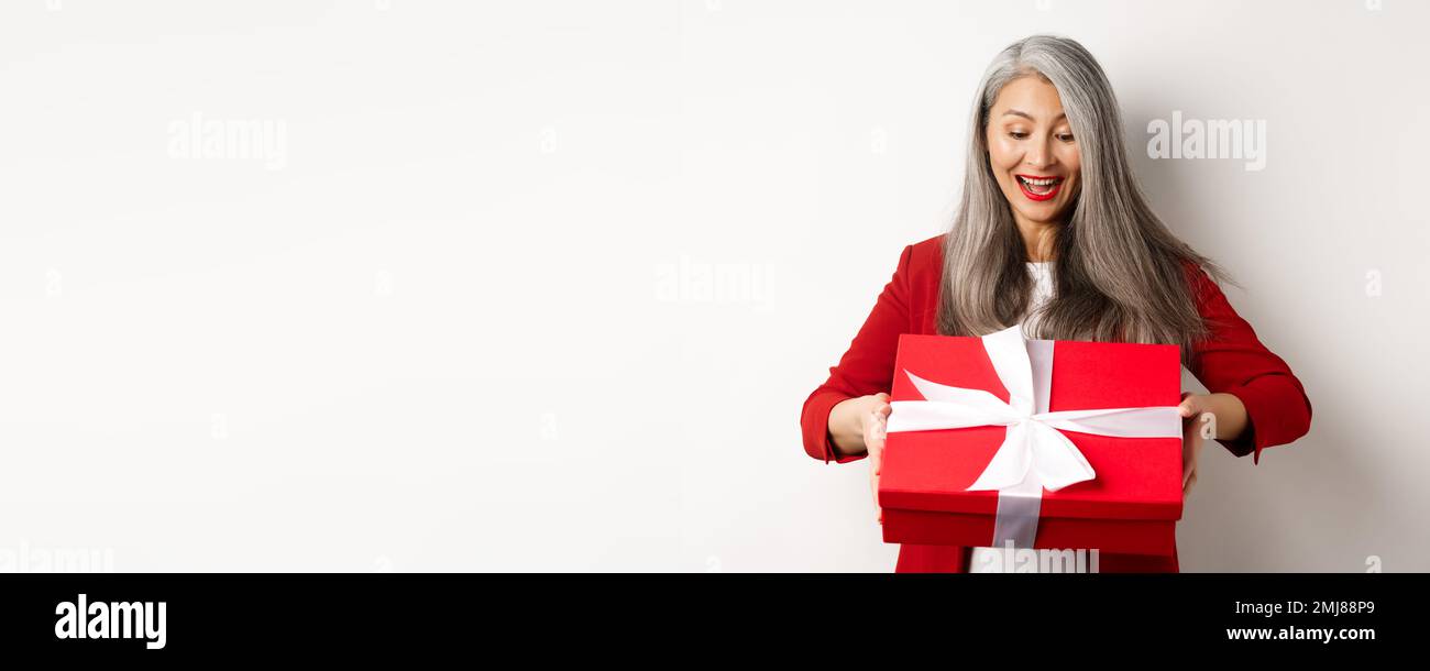 Happy elderly woman with grey hair, receive present, looking at red ...