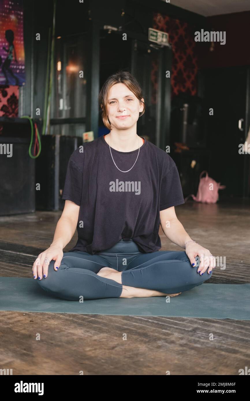 Vertical photo of a smiley female new yoga teacher resting in easy pose ...